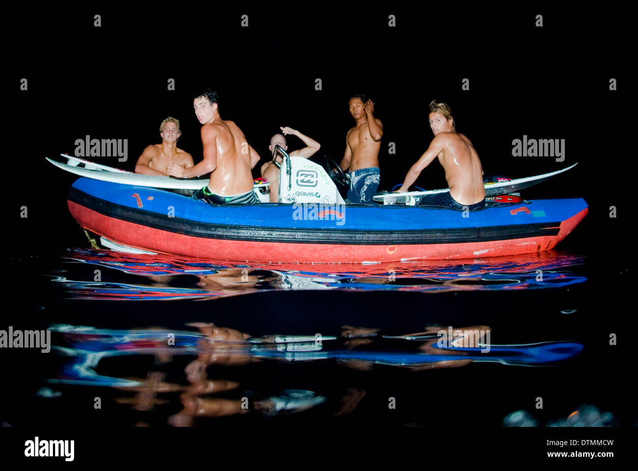 five guys dudes on a small boat with surfboards in the ocean sea water ...