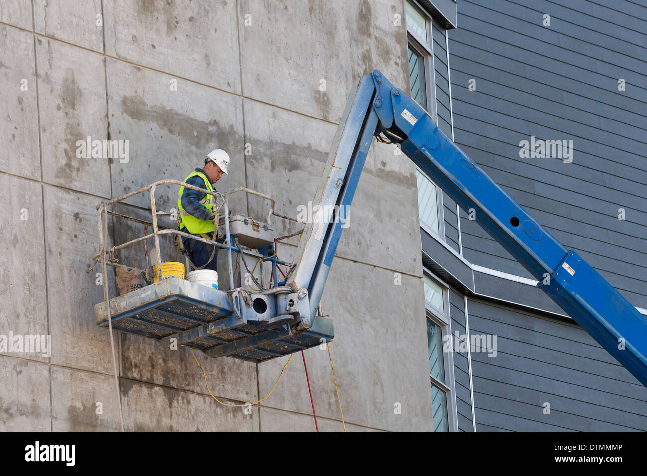Construction worker working on platform on side of concrete building ...