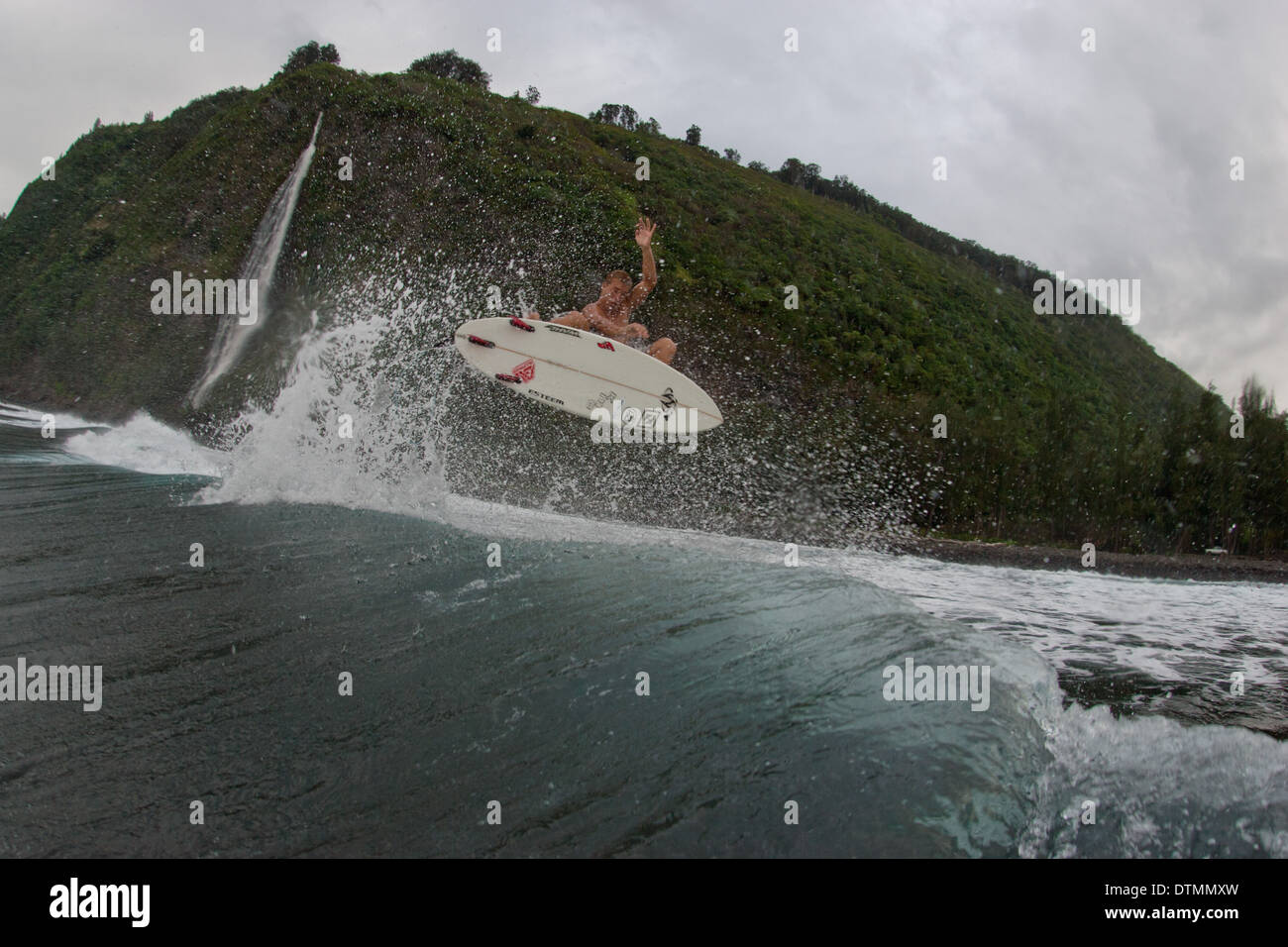 surfer catches some air as he jumps on his surfboard in hawaii with a ...