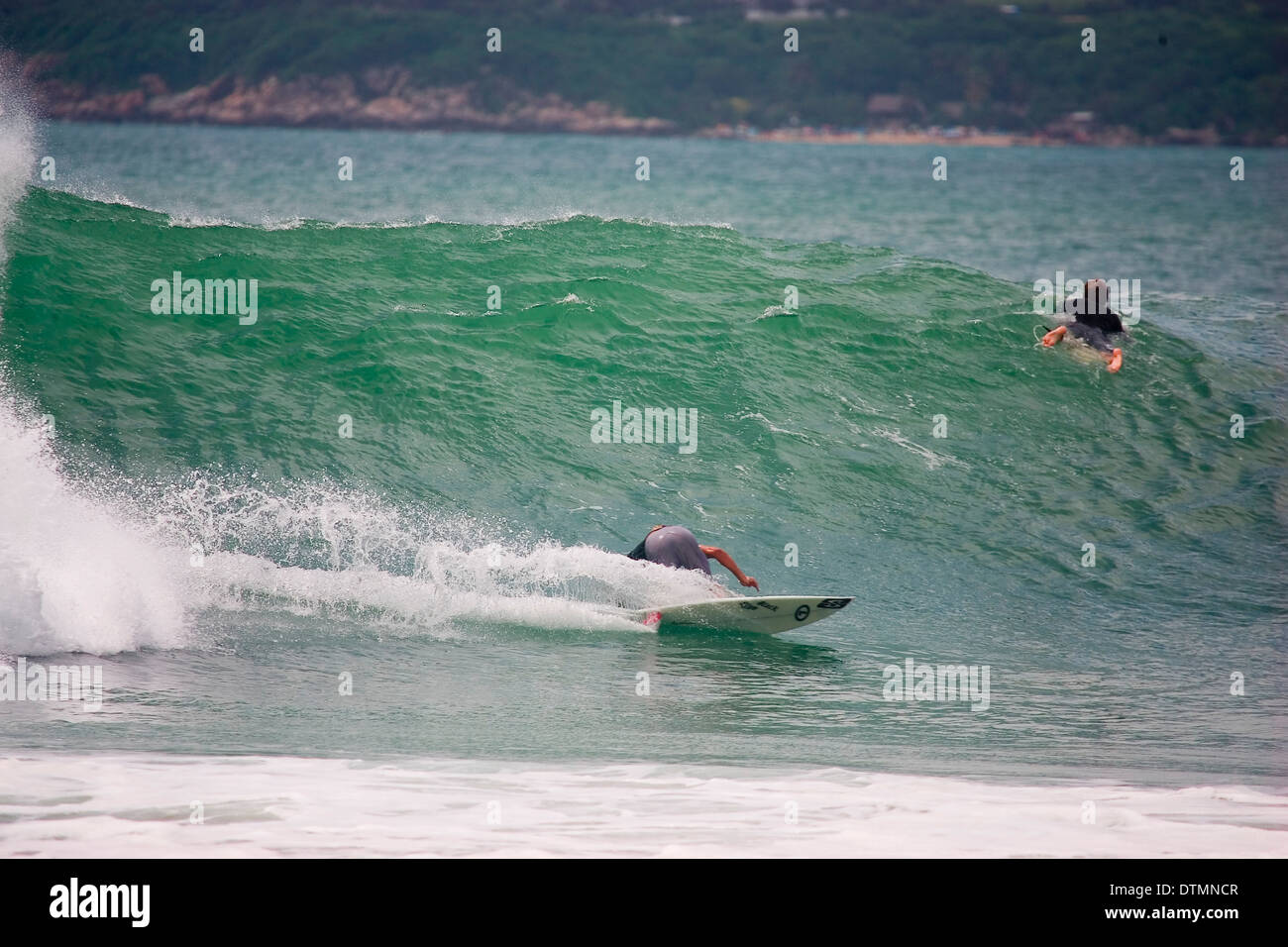 surfer whips his surfboard in the ocean sea water with some tricks in a ...