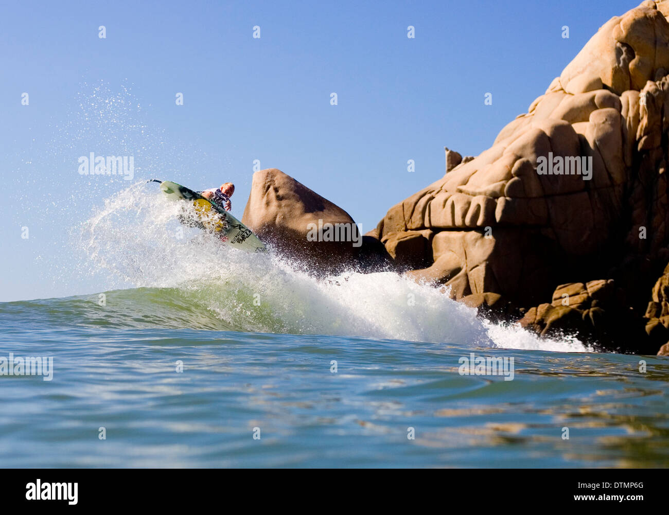 surfer jumping in a wave in the ocean water sea with large rocks ...