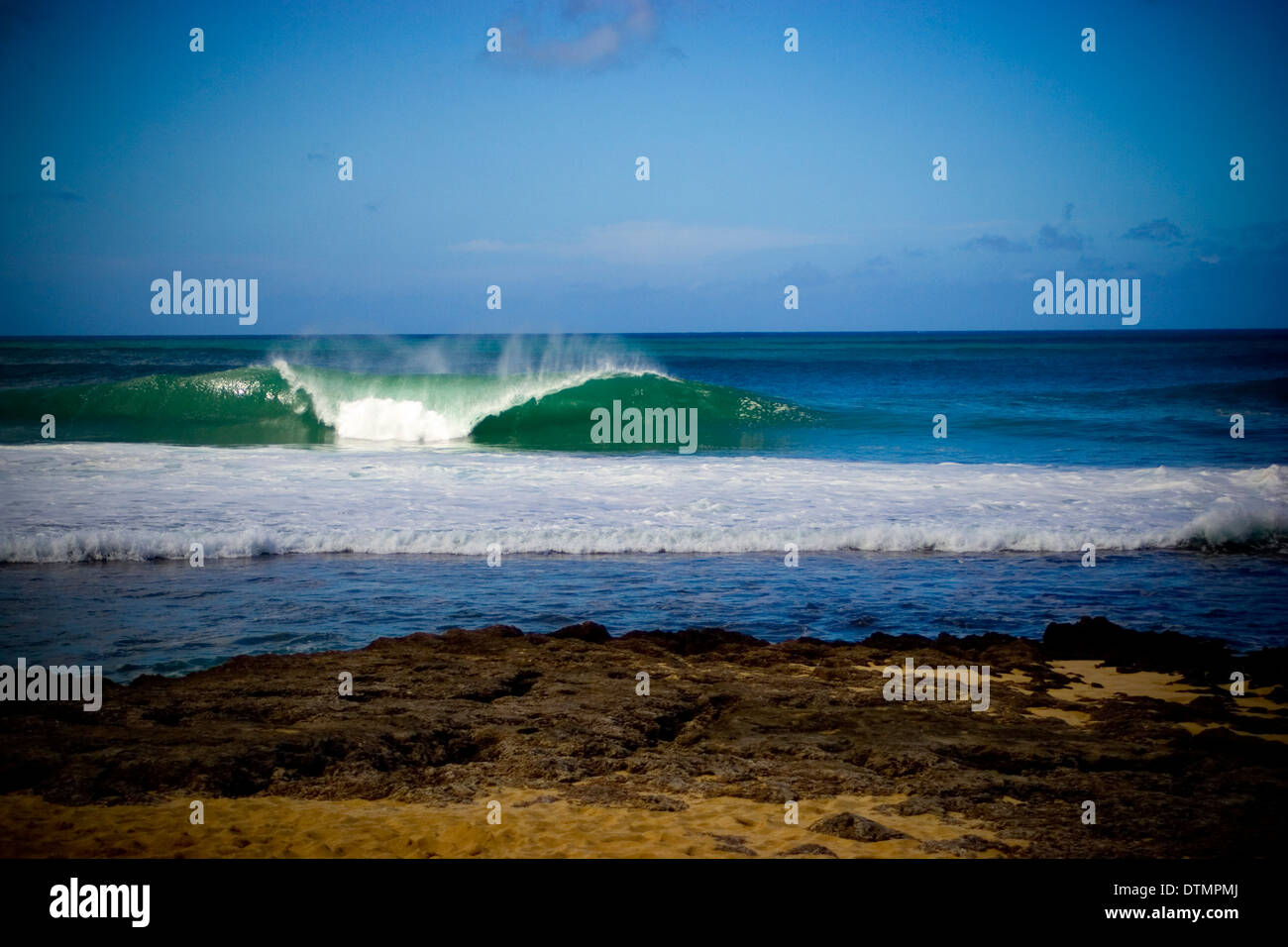 wave curls in hawaii by the brown and tan sand Stock Photo - Alamy