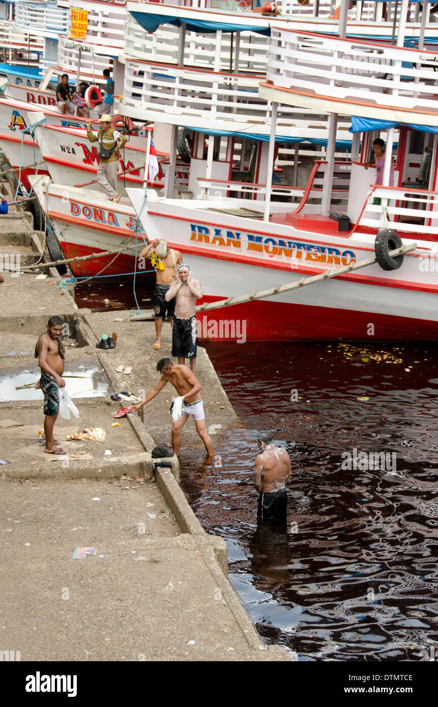 Brazil, Amazon, Manaus. Busy waterfront pier. Local workers bathing in ...