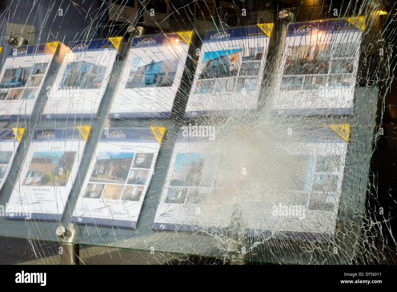 smashed glass window in an estate agents shop front Stock Photo - Alamy