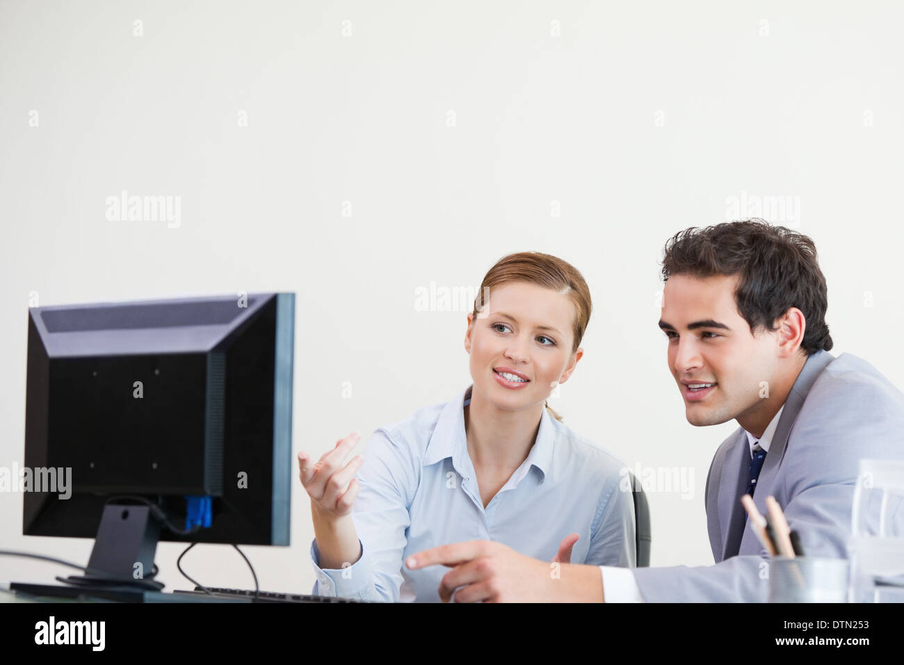 Colleagues pointing something on a computer Stock Photo - Alamy
