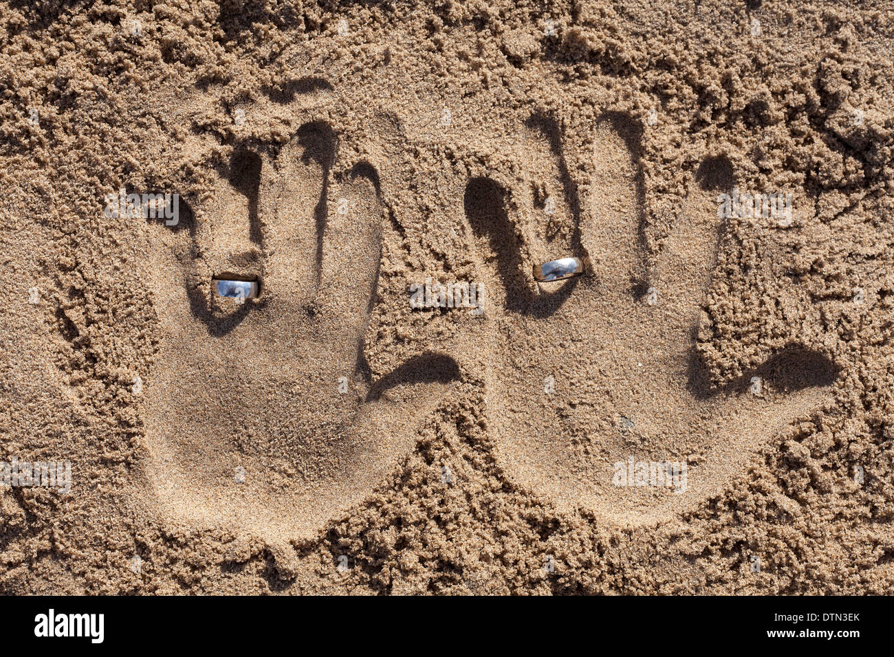 Warm textured sand with hands pressed in showing wedding rings Stock ...
