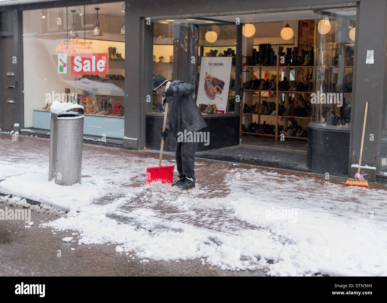A shop worker in Amsterdam clearing snow Stock Photo - Alamy