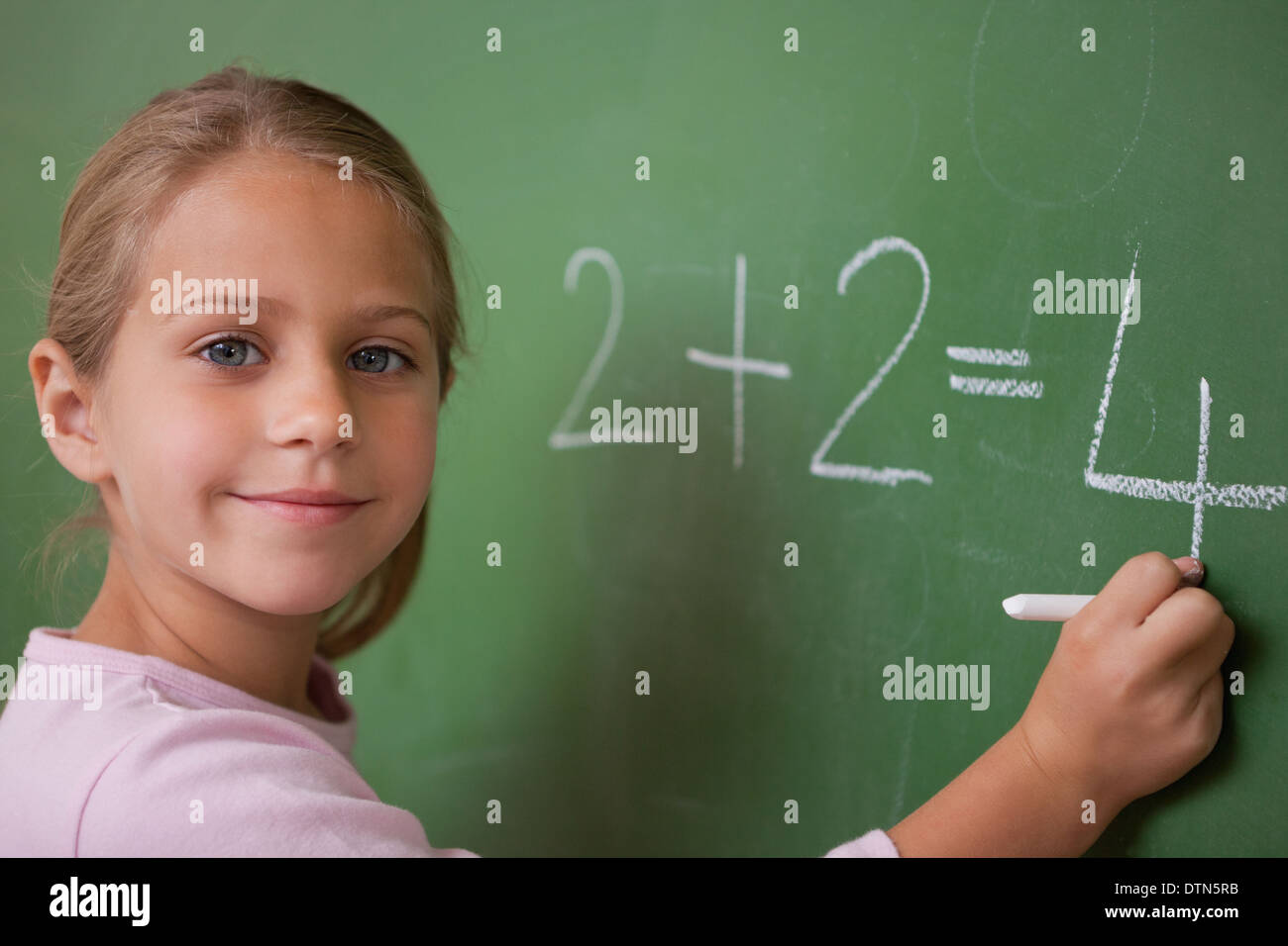 Smiling schoolgirl writing a number Stock Photo - Alamy