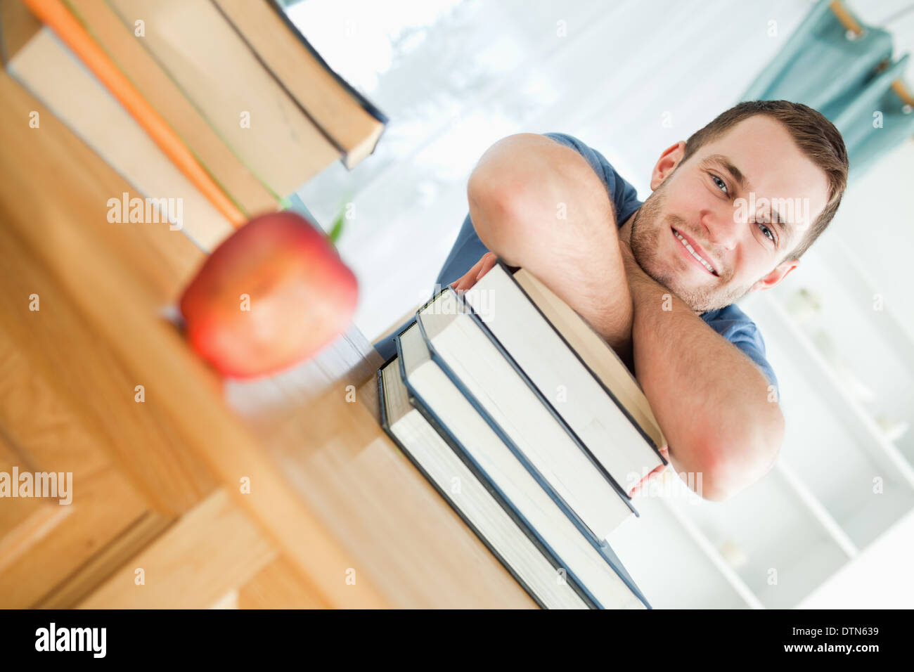 Smiling student with a pile of books Stock Photo - Alamy