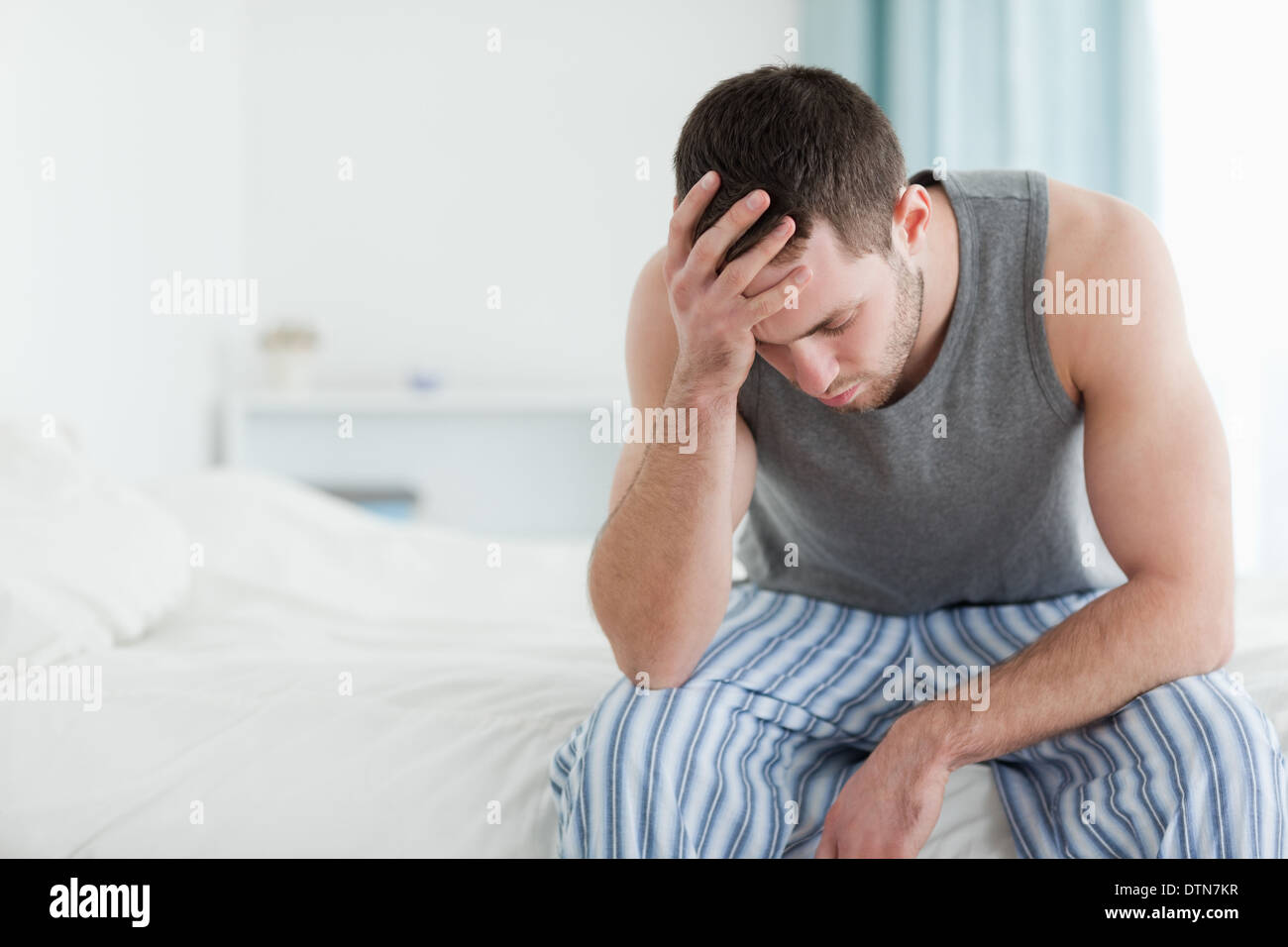 Sad man sitting on his bed Stock Photo - Alamy