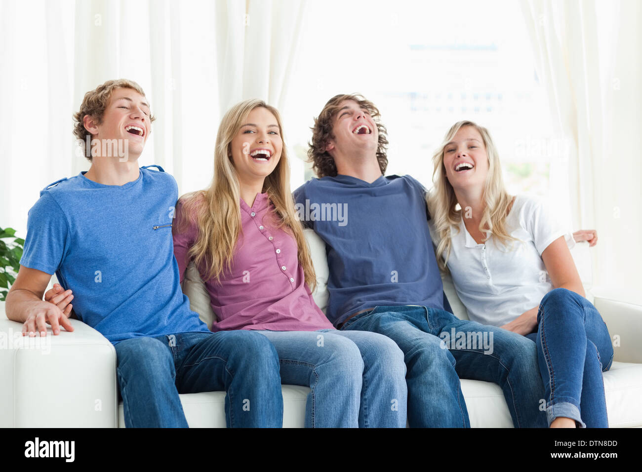 Laughing friends sit on the couch together Stock Photo - Alamy