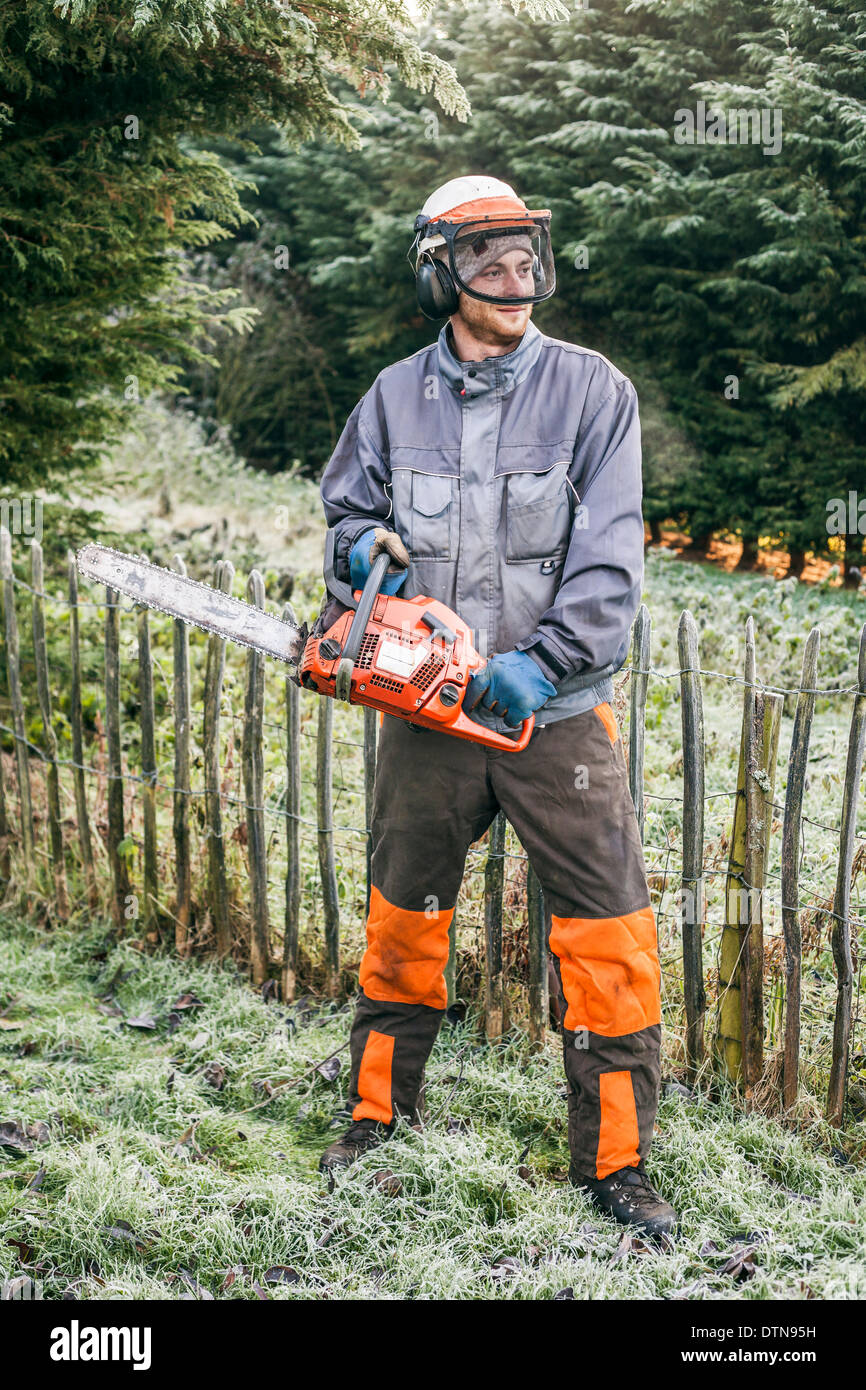 Portrait of professional gardener with chainsaw standing in the garden ...