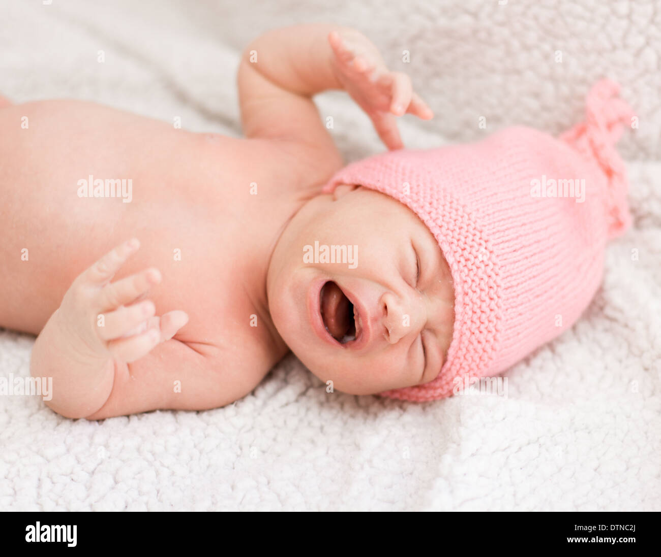 Portrait of crying newborn baby girl with pink hat Stock Photo - Alamy