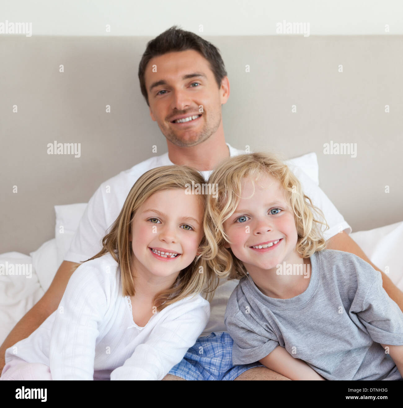 Father sitting on bed with his children Stock Photo - Alamy
