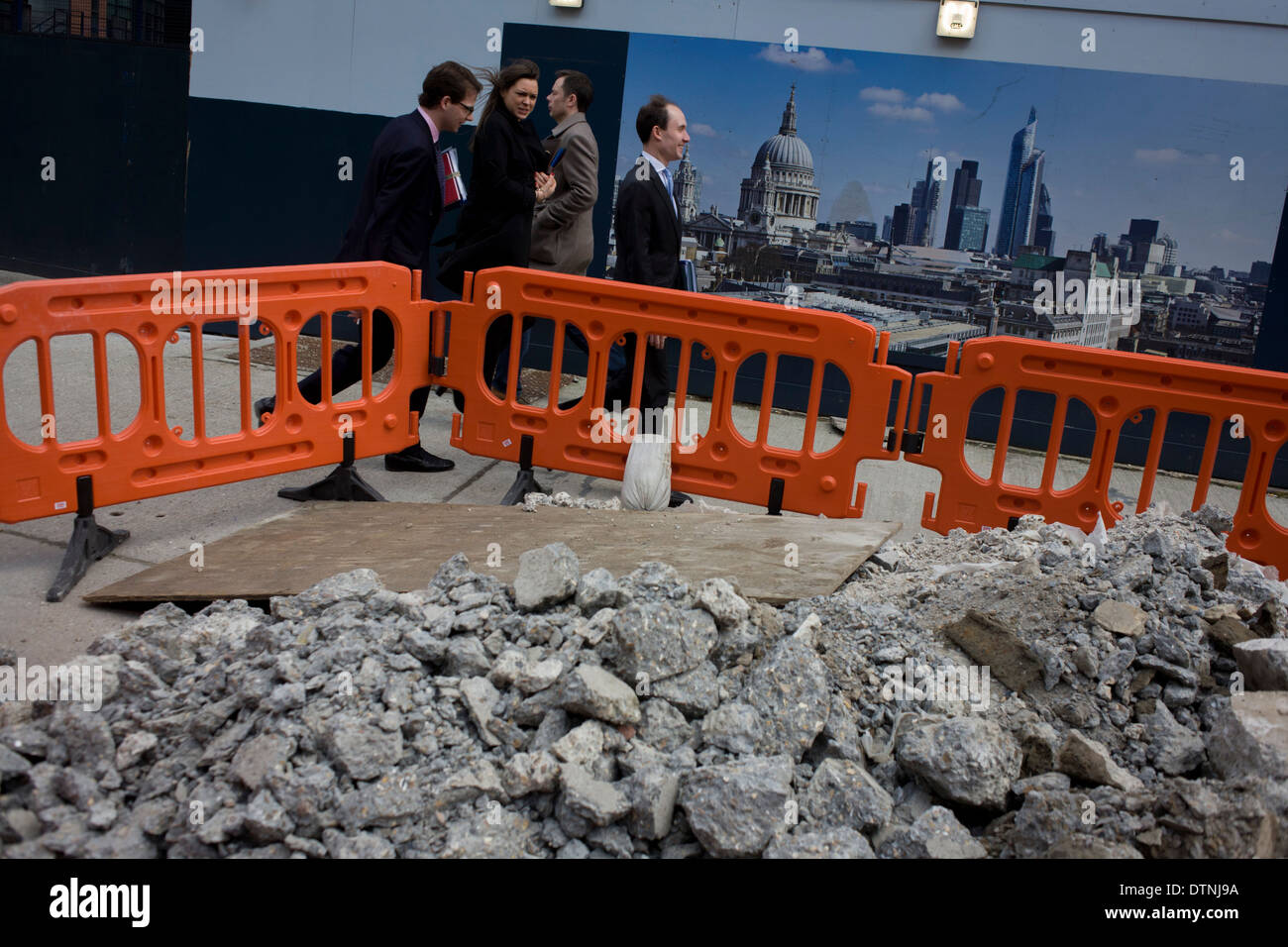 City workers walk past a pile of construction rubble near an skyline ...