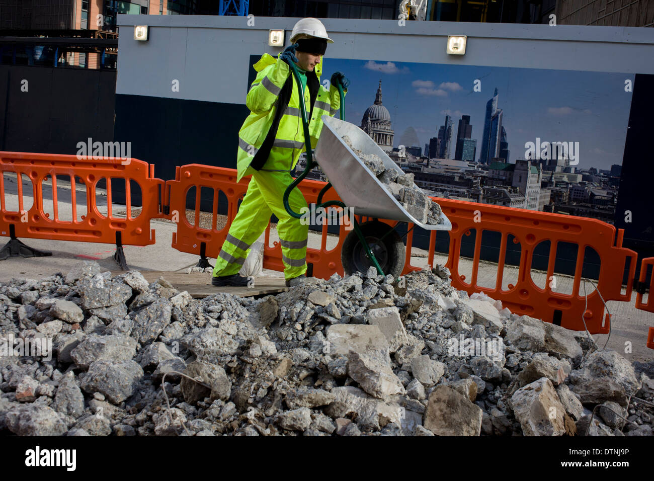 A workman tips broken up concrete on to a growing pile of construction ...