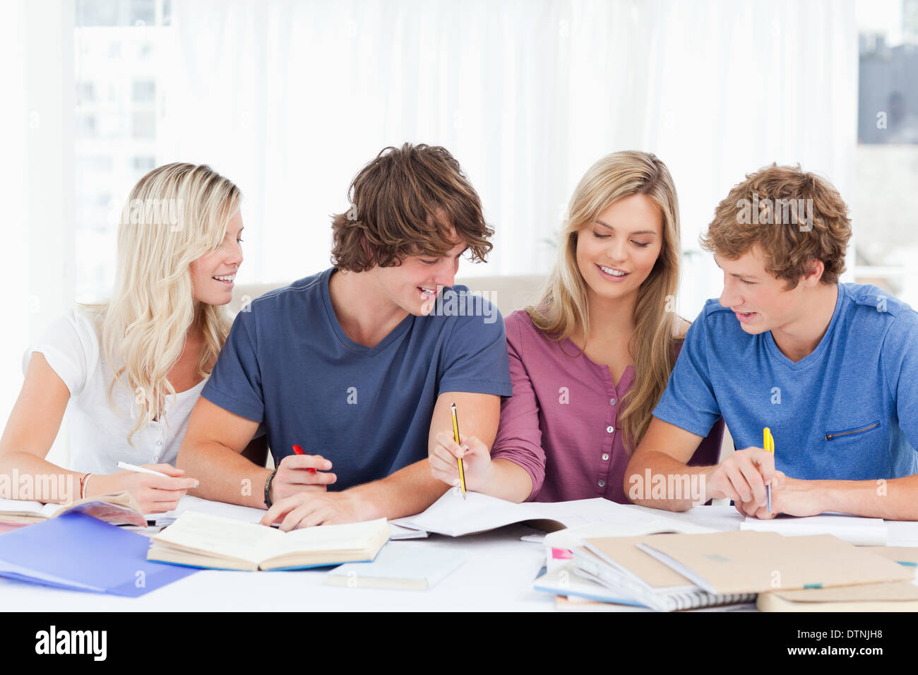 Four students laughing as they work together Stock Photo - Alamy
