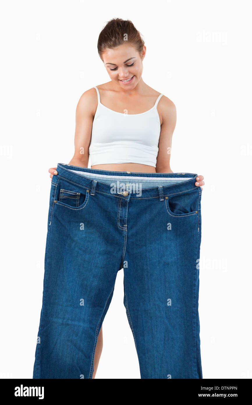 Portrait of a fit woman showing large jeans Stock Photo - Alamy
