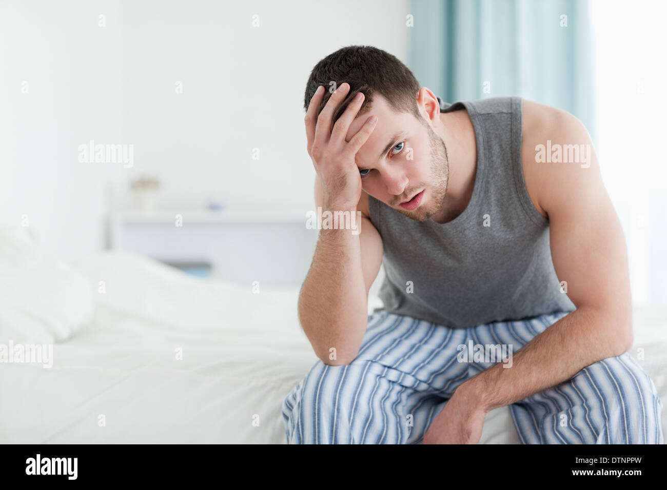 Tired man sitting on his bed Stock Photo - Alamy