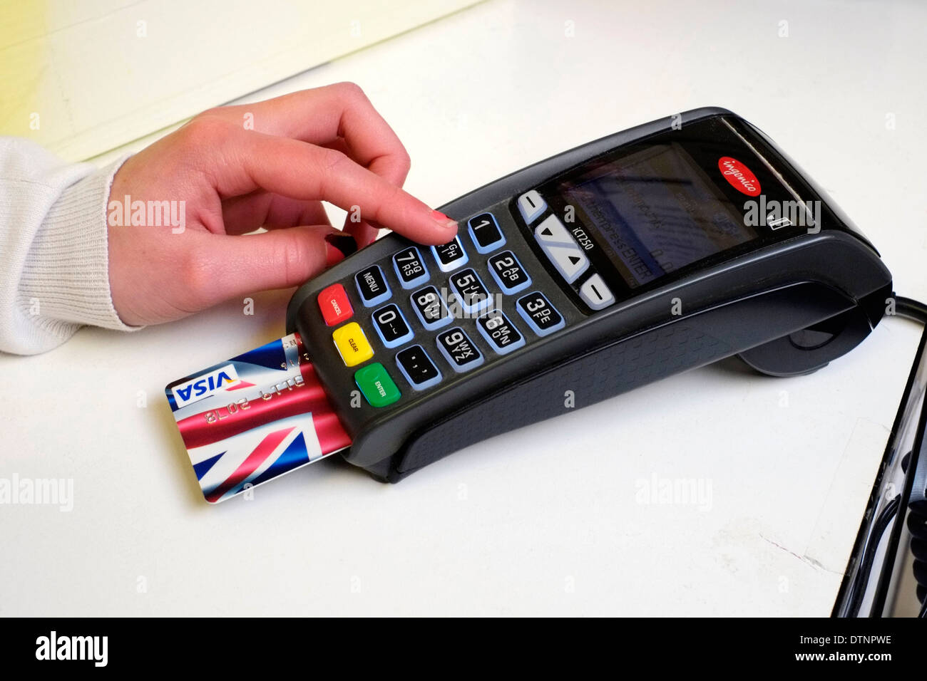 young woman keying in pin number into card reader with union jack flag ...