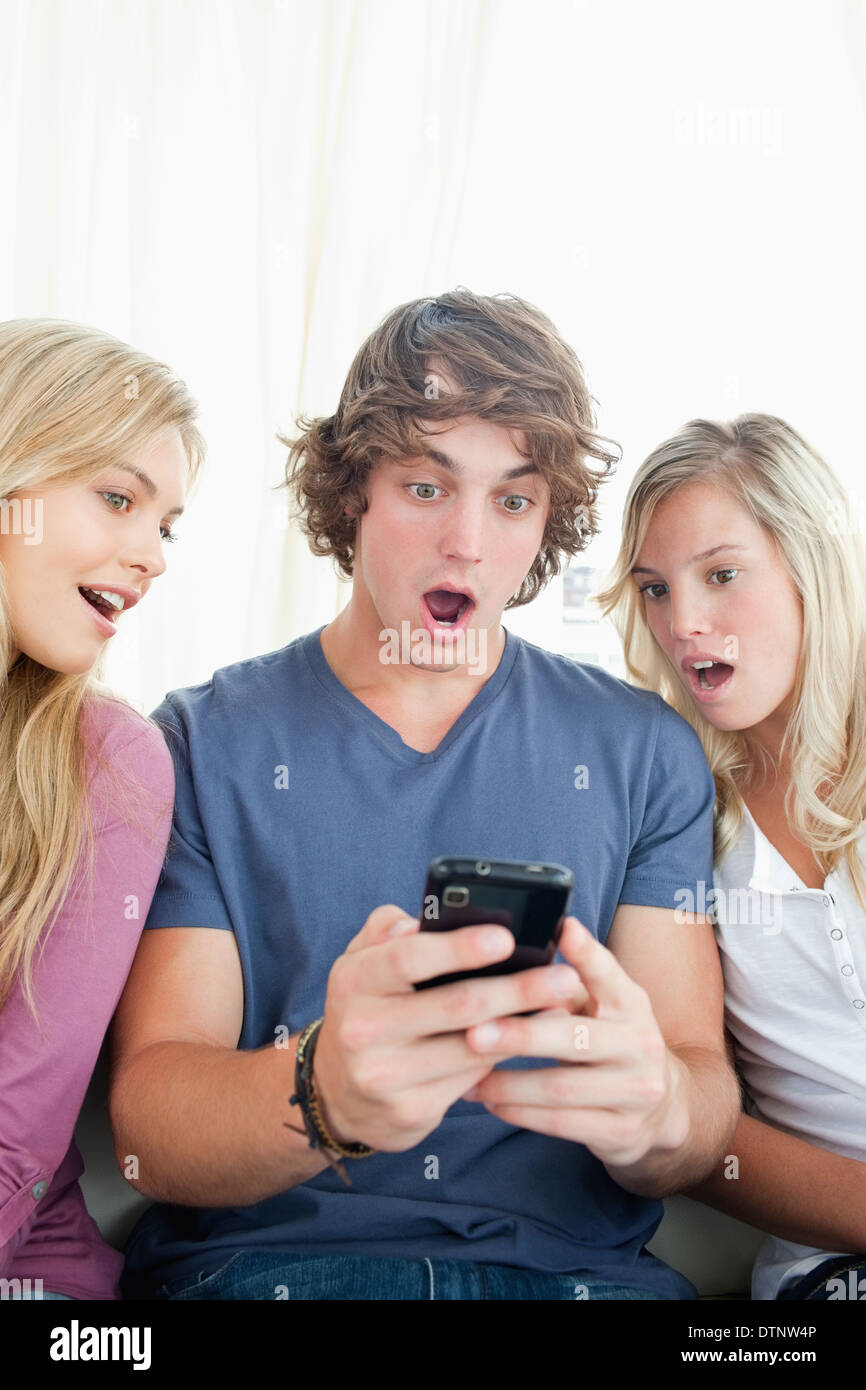 Shocked friends look at the man's phone Stock Photo - Alamy