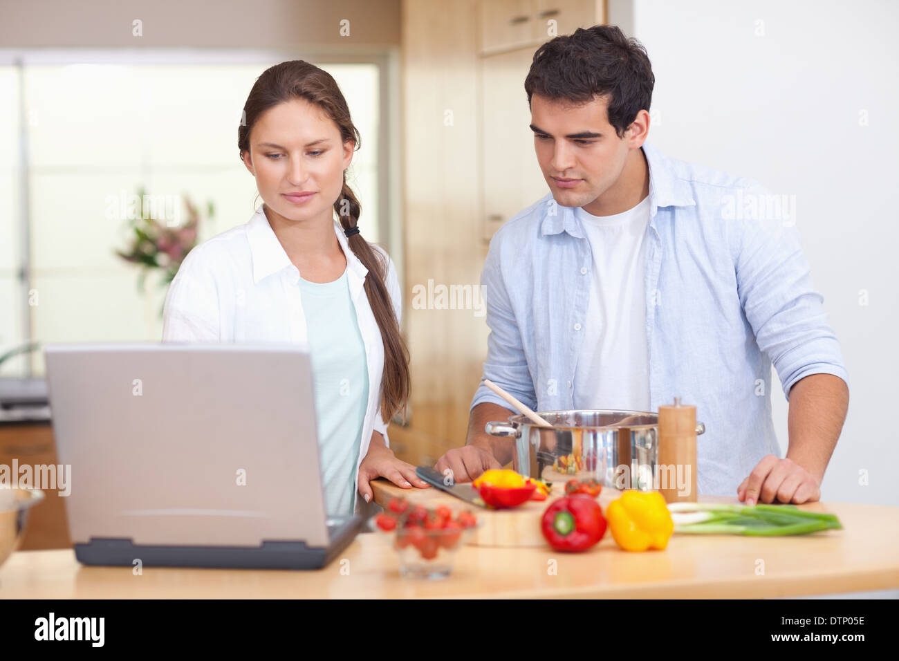 Couple using a laptop to cook Stock Photo - Alamy