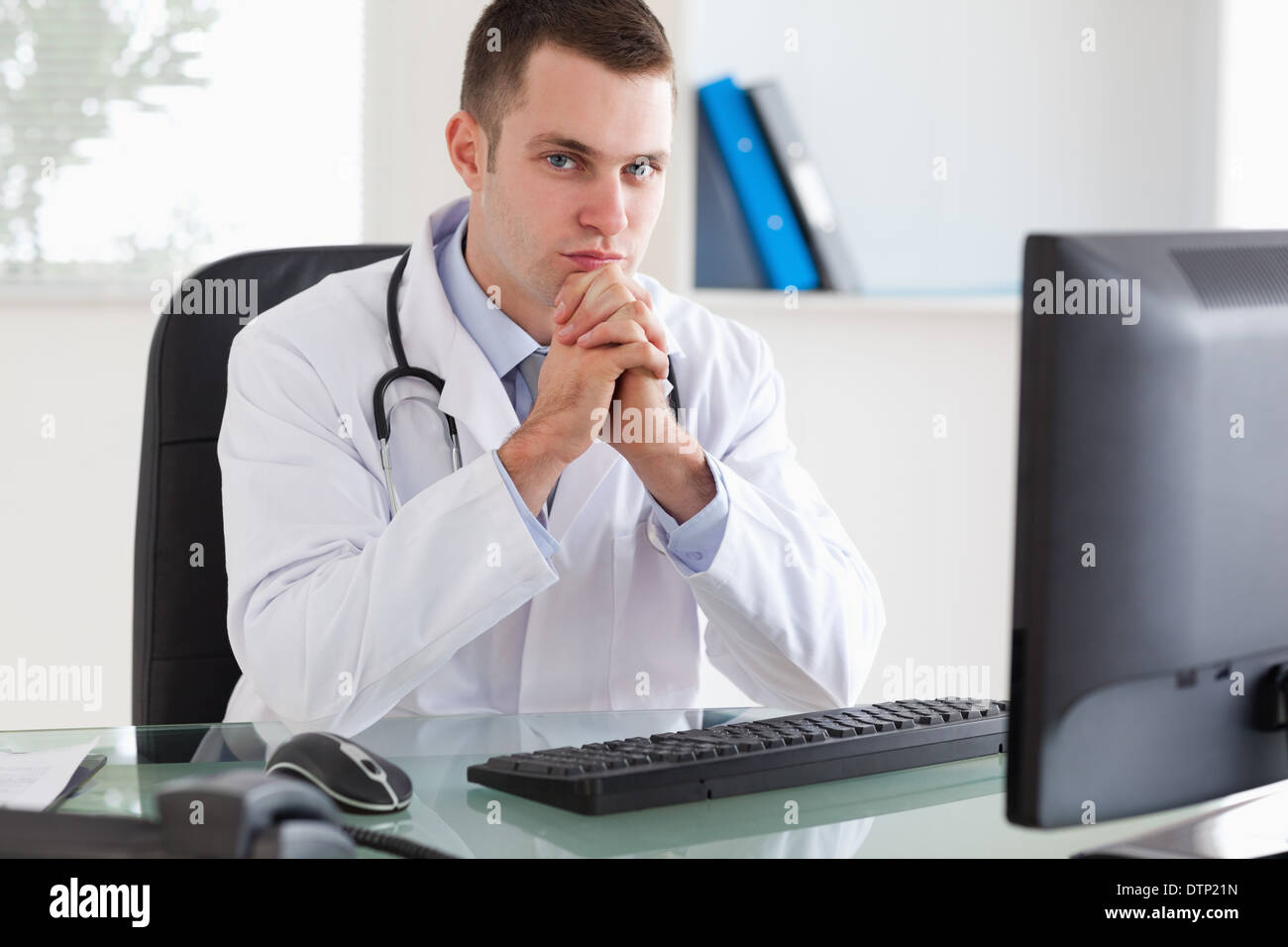 Doctor sitting behind his desk Stock Photo - Alamy