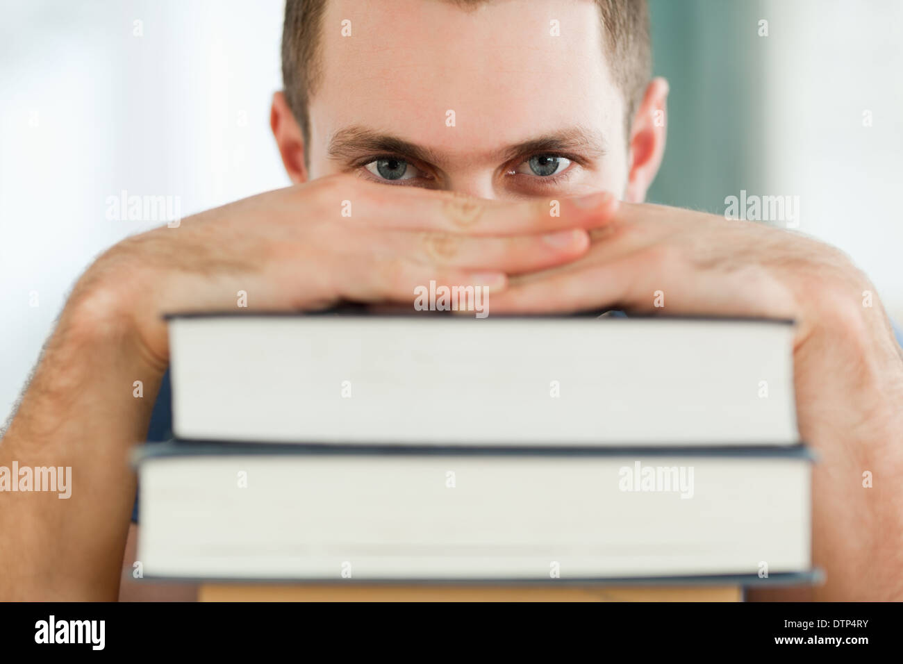 Student hiding behind a pile of books Stock Photo - Alamy