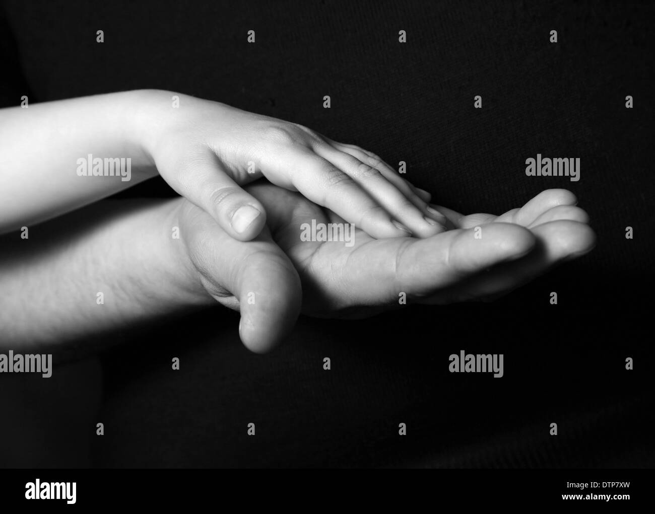 Hand of the adult person and hand of the small child on a dark ...