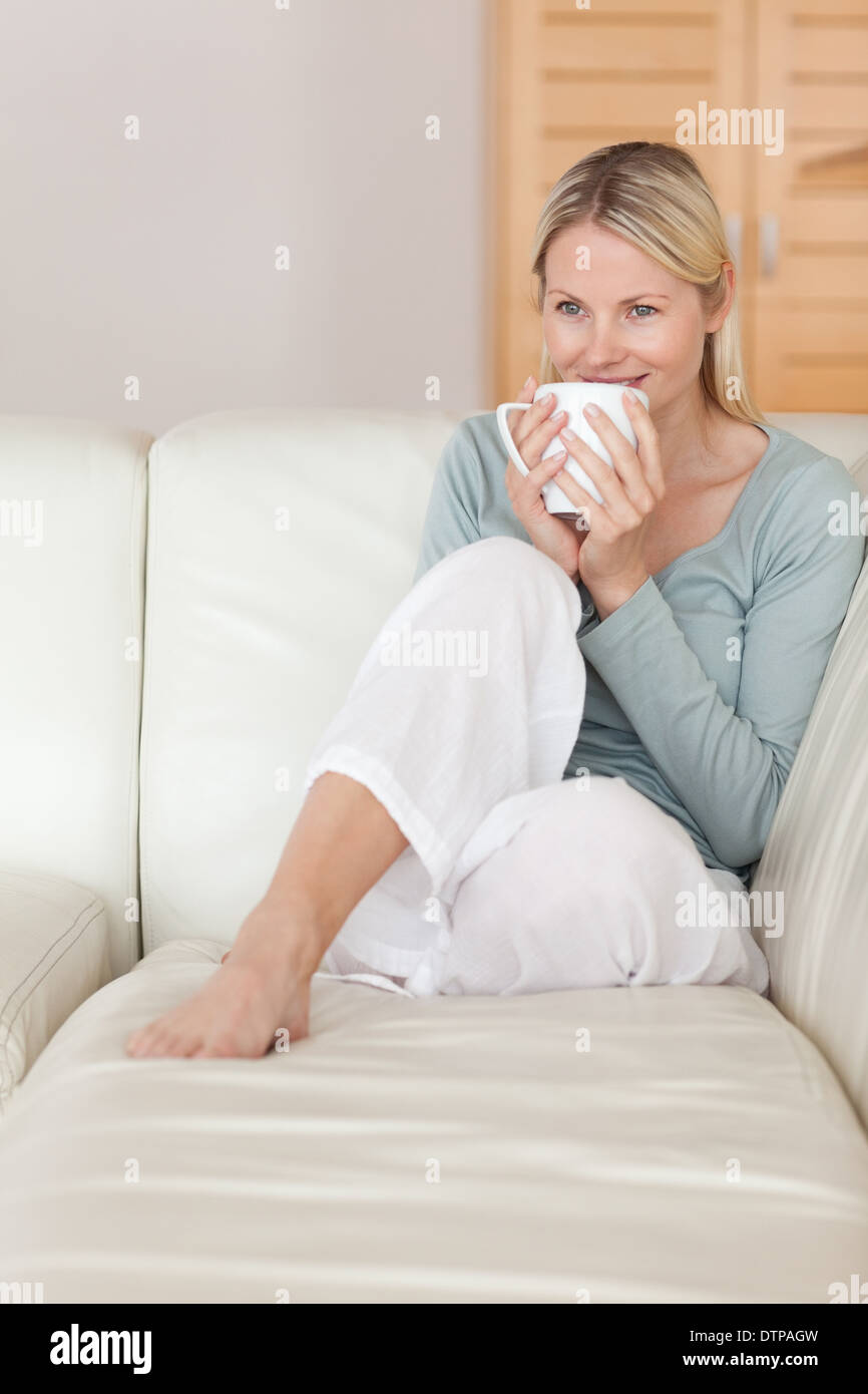 Woman taking a sip of coffee on the sofa Stock Photo - Alamy