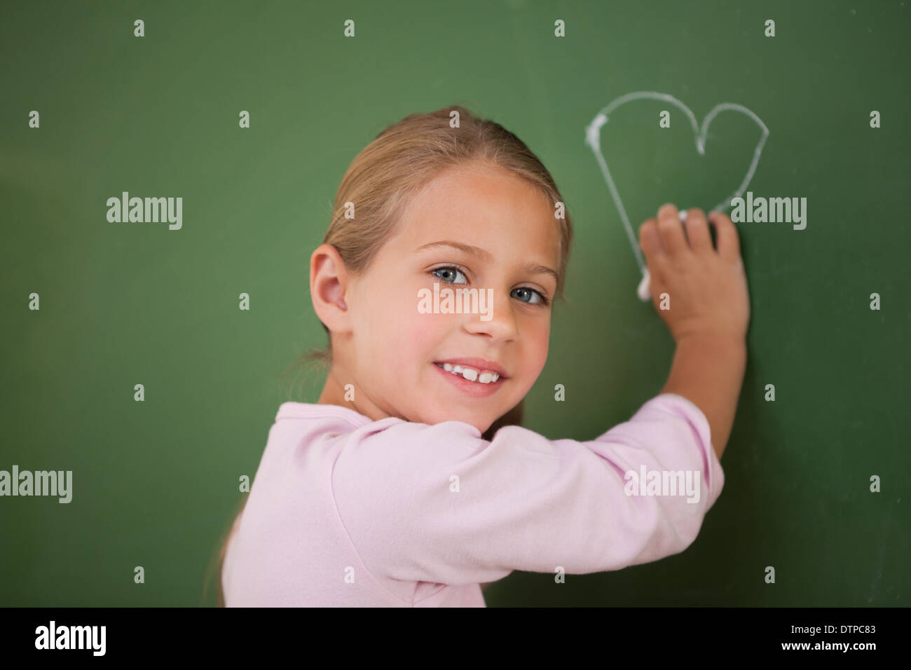 Smiling schoolgirl drawing a heart Stock Photo - Alamy