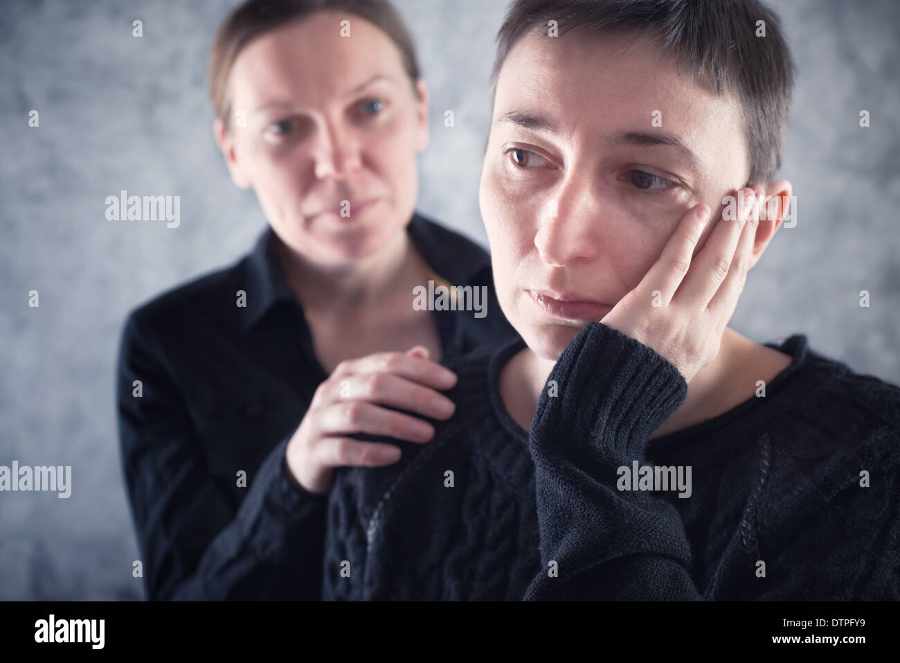 Comforting friend. Woman consoling her sad friend with hand on shoulder ...