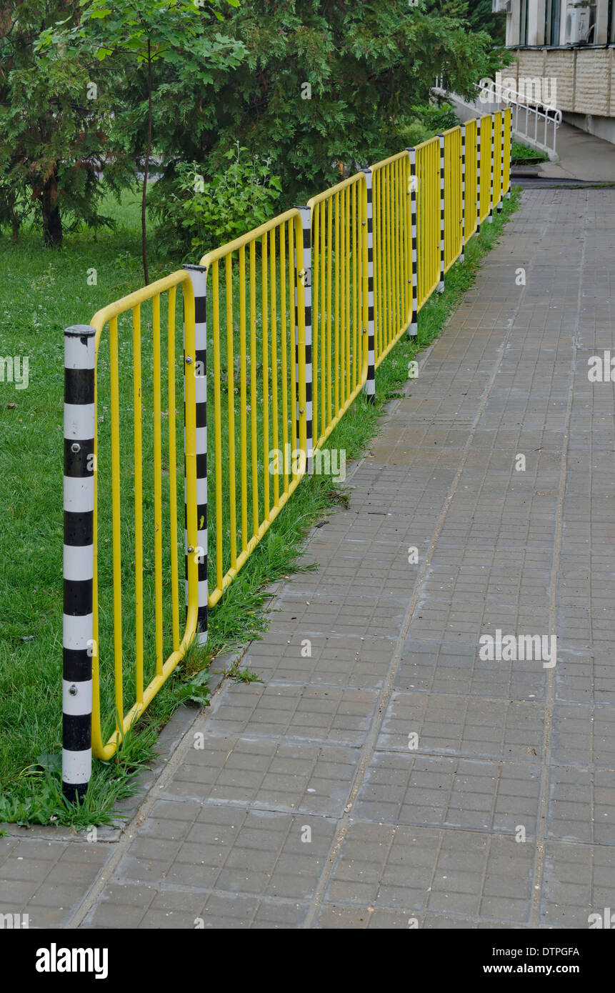 Metal fence by path in town garden Stock Photo - Alamy