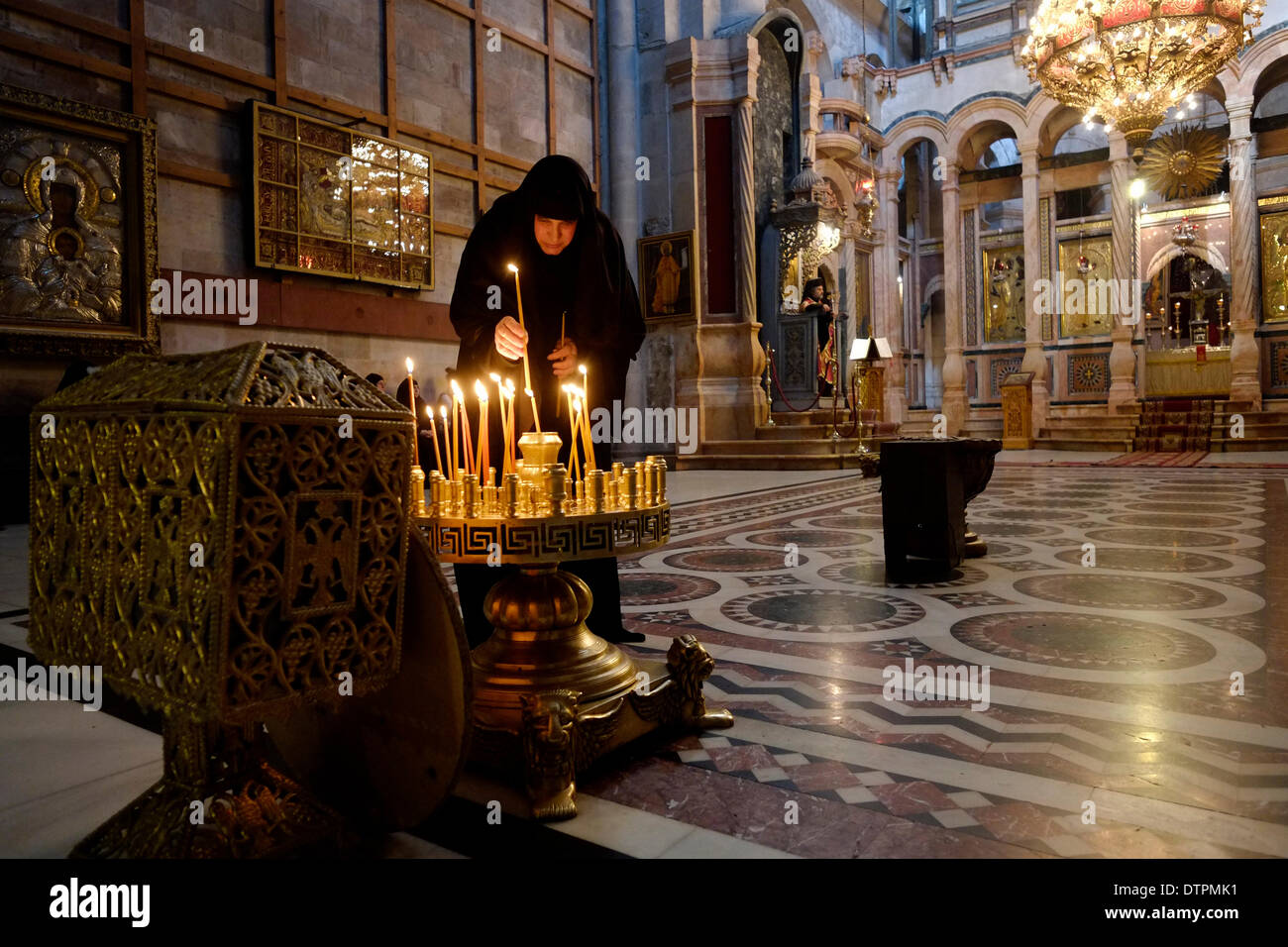 An Eastern Orthodox Christian worshiper lights candles during a mass ...