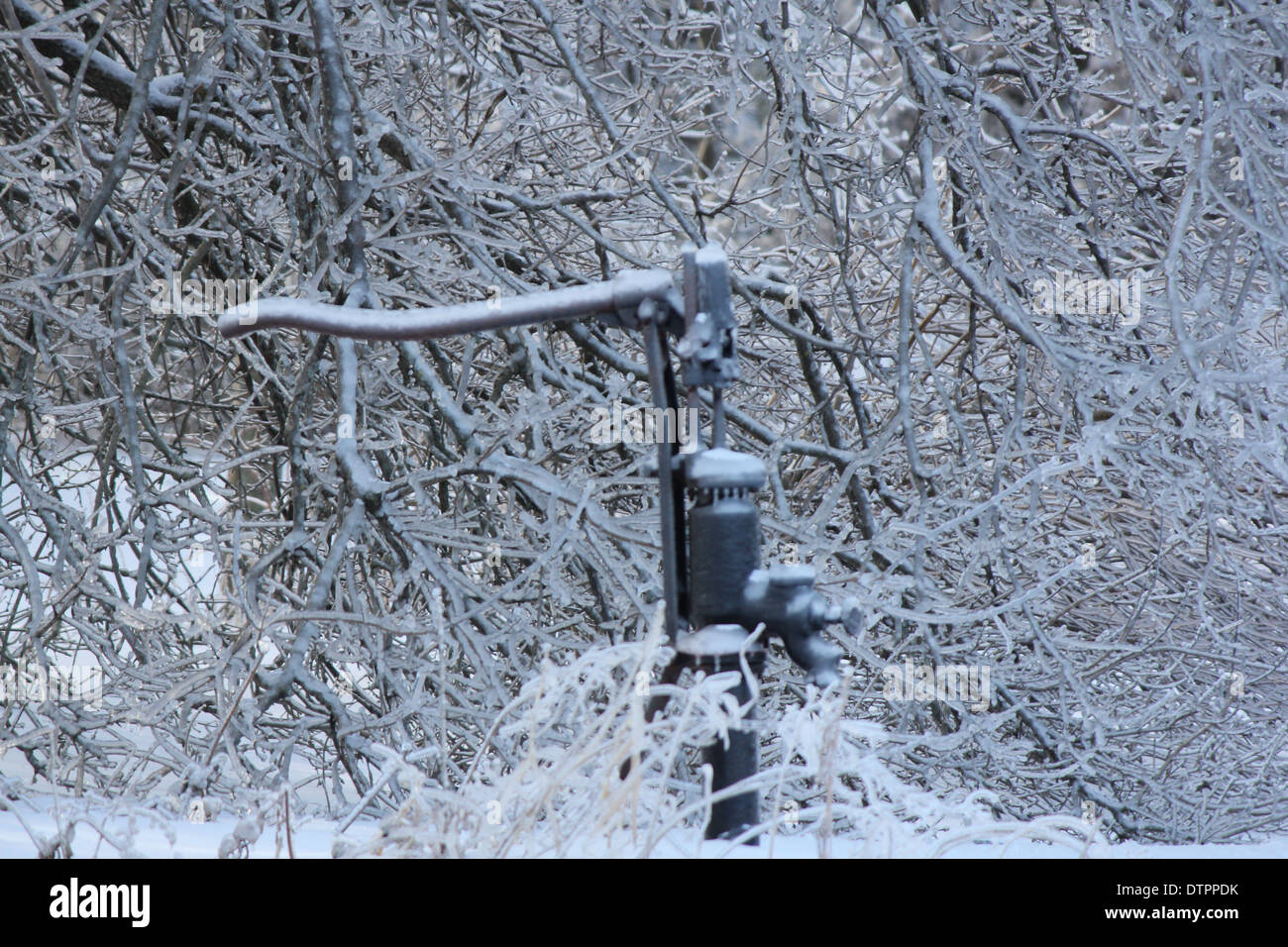 Ice and snow covering an ancient deep well water pump in a corner of a ...