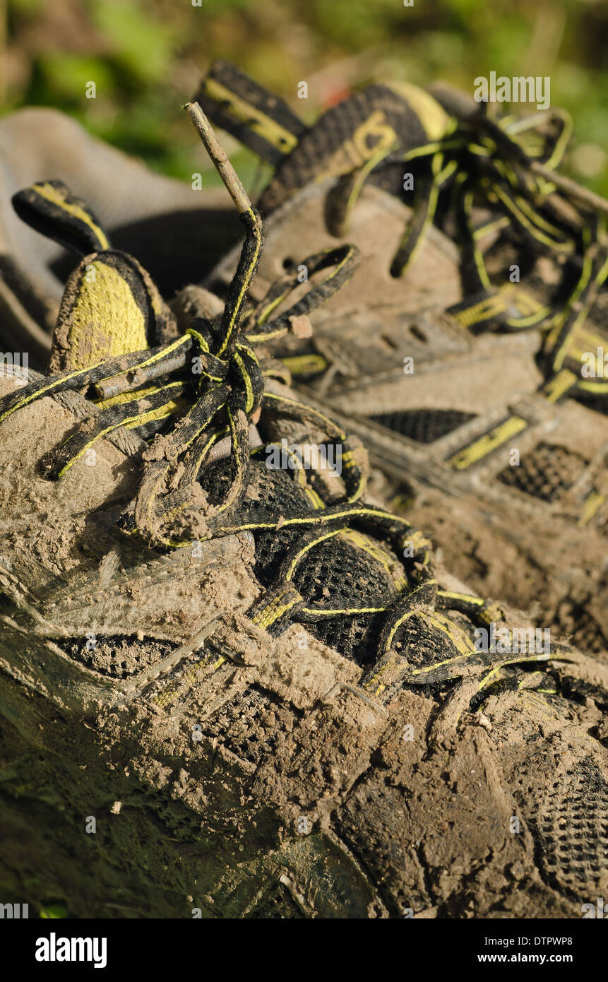 Muddy running shoes coated in mud from cross country training showing ...