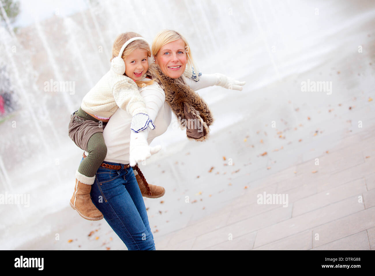 happy mum giving smiling winter child piggyback Stock Photo - Alamy