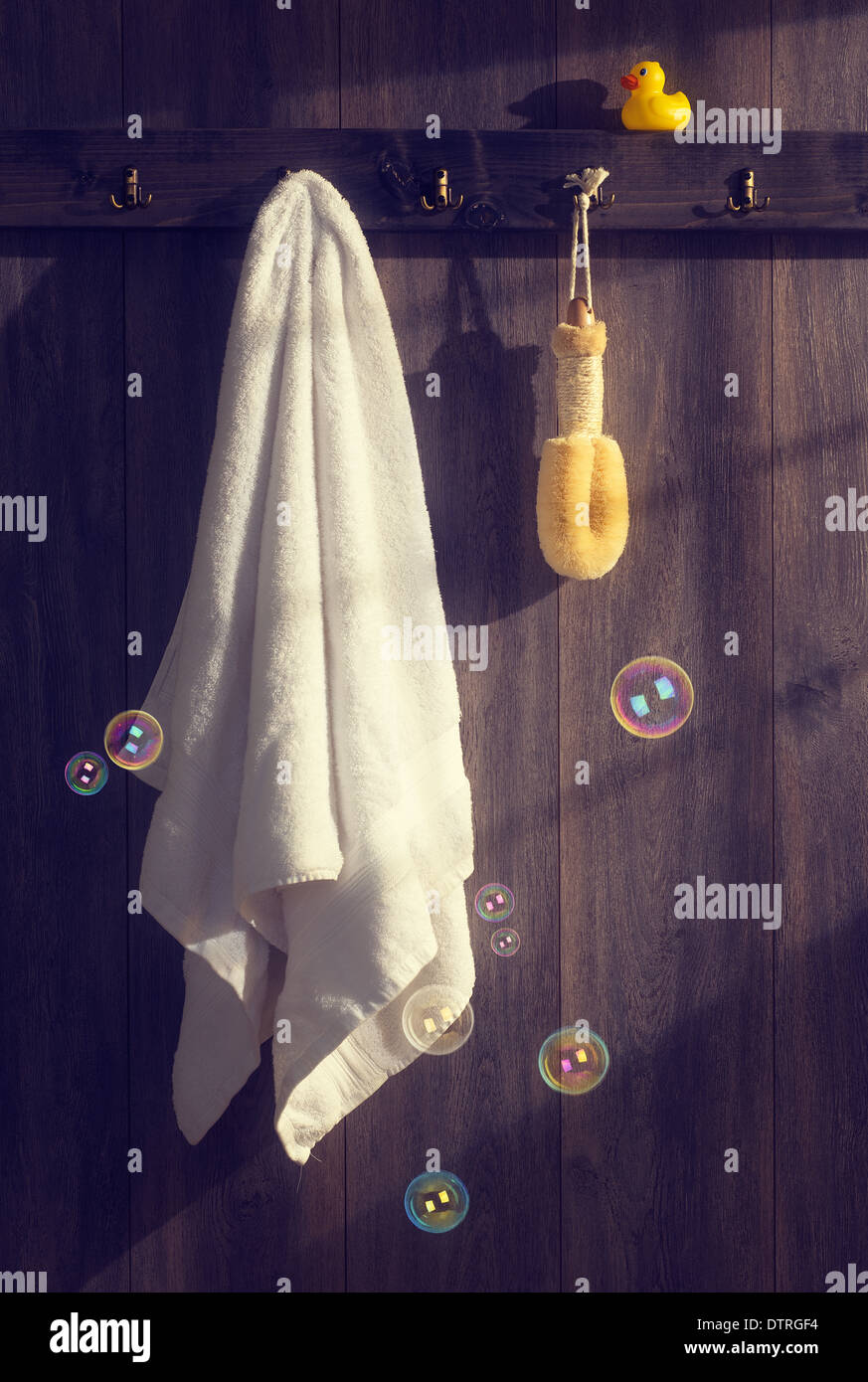 White towel with loofah hanging on wall with floating bubbles and ...