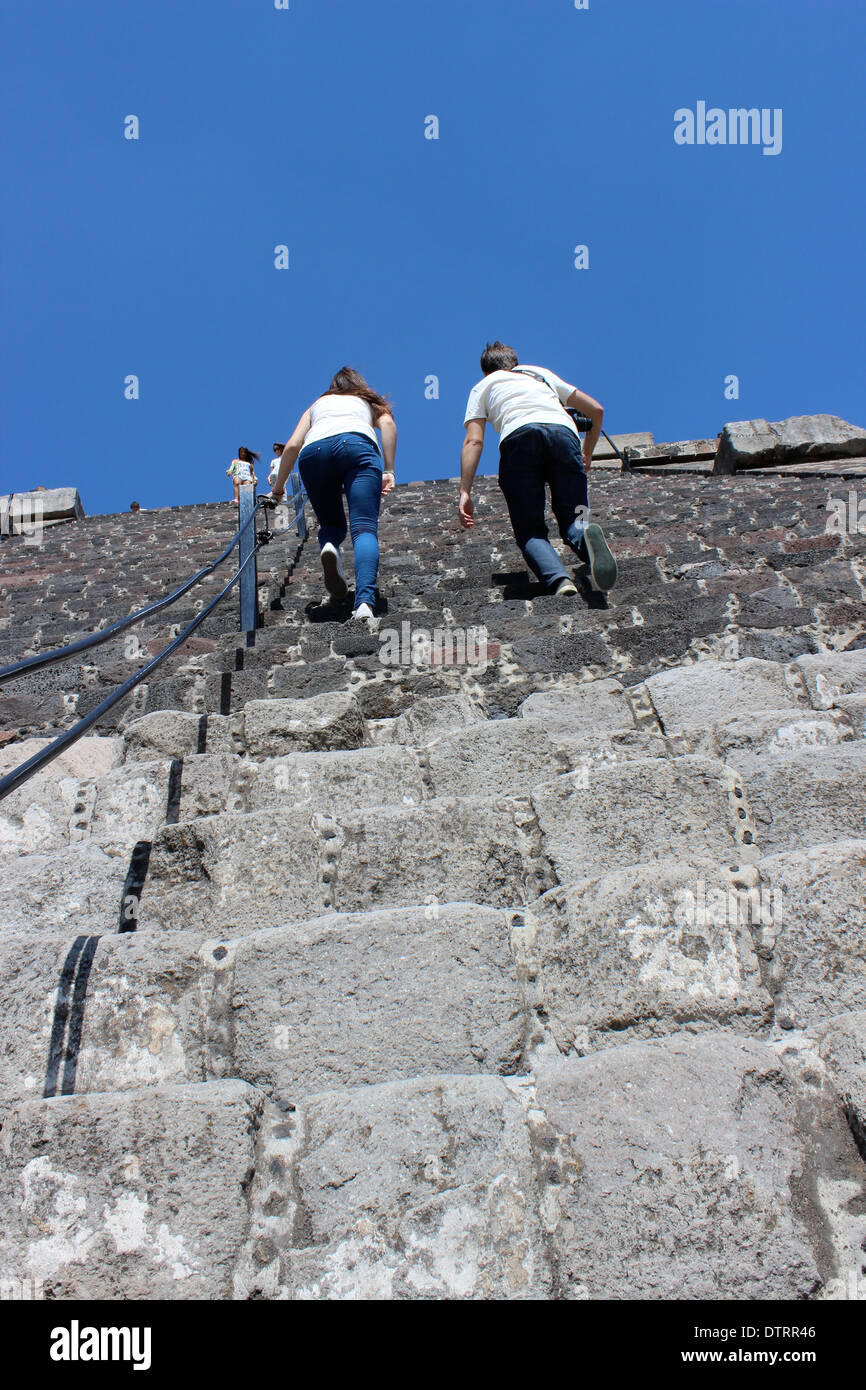 Two people climbing up the stone steps of the Moon Pyramid, Teotihuacan ...