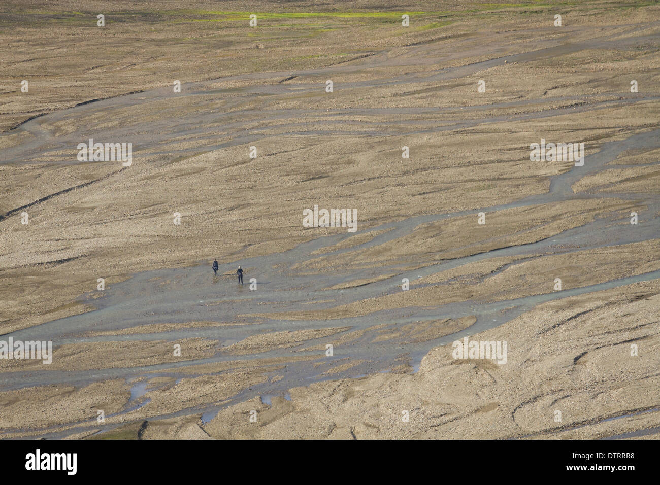 Two hikers are walking through a river with different streams in ...