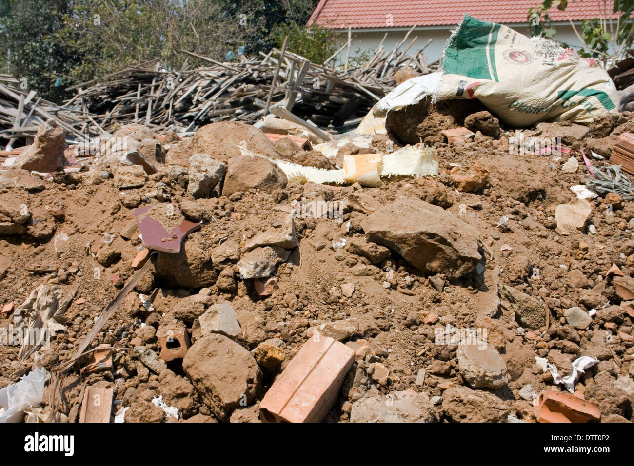 A pile of dirt strewn with bricks rests in front of a stack of wood ...