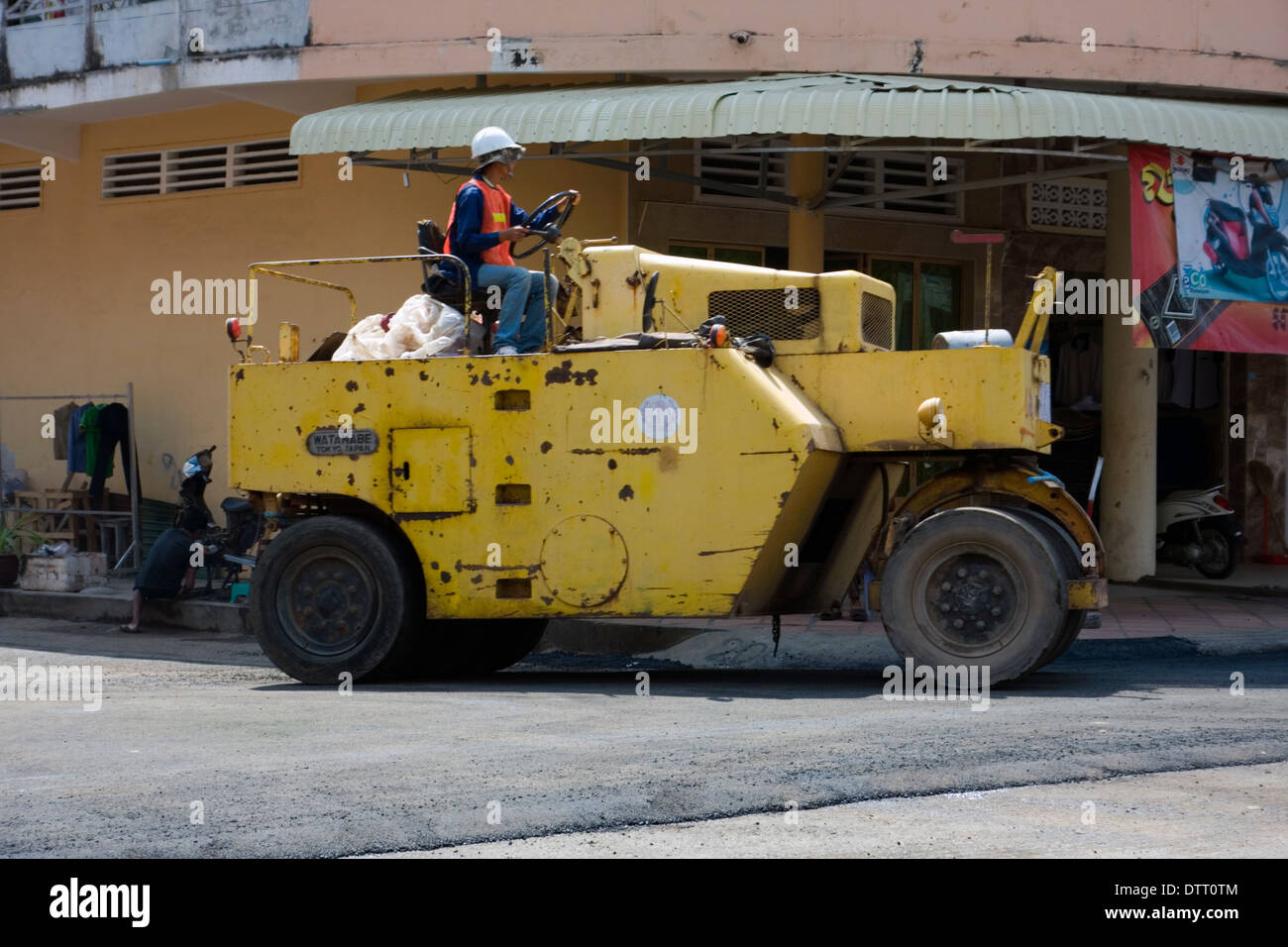 A man is driving a Japanese made Watanabe roller on new pavement on a ...
