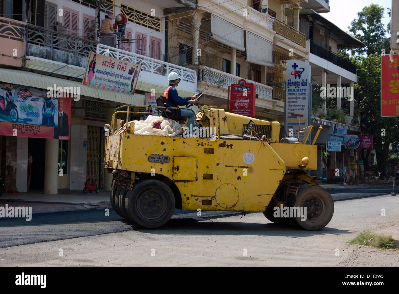 A man is driving a Japanese made Watanabe roller on new pavement on a ...