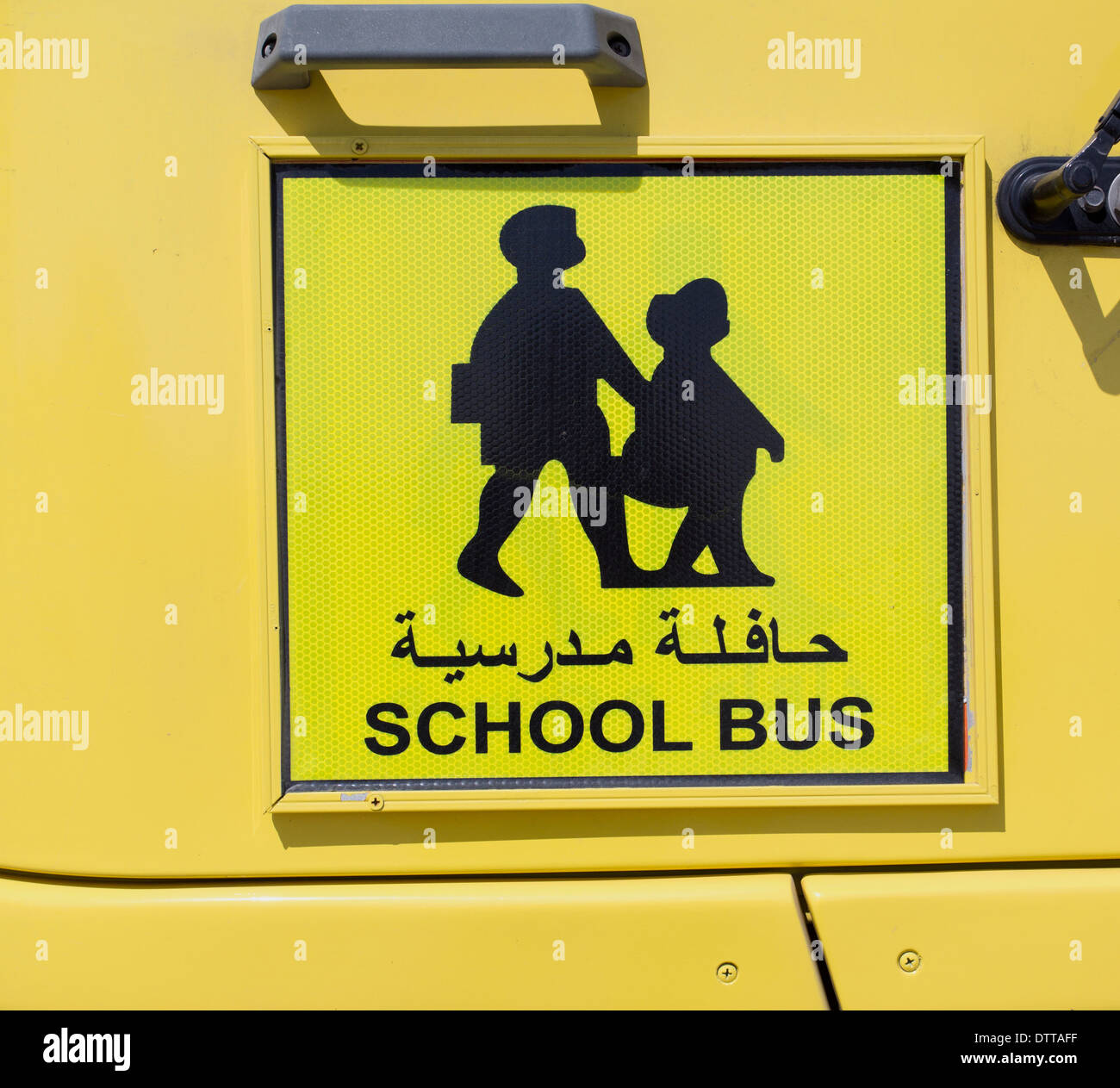 A School bus sign on the front of a yellow school bus, in Arabic and ...
