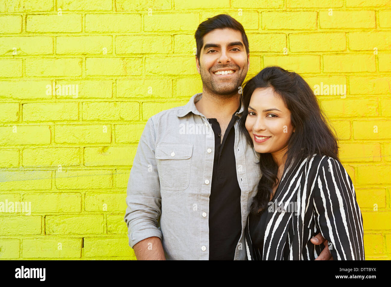 Indian couple hugging in front of yellow brick wall Stock Photo - Alamy