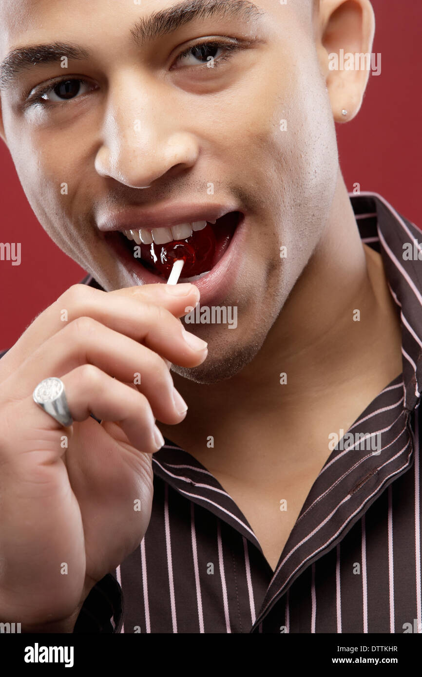 Mixed race man eating lollipop Stock Photo - Alamy