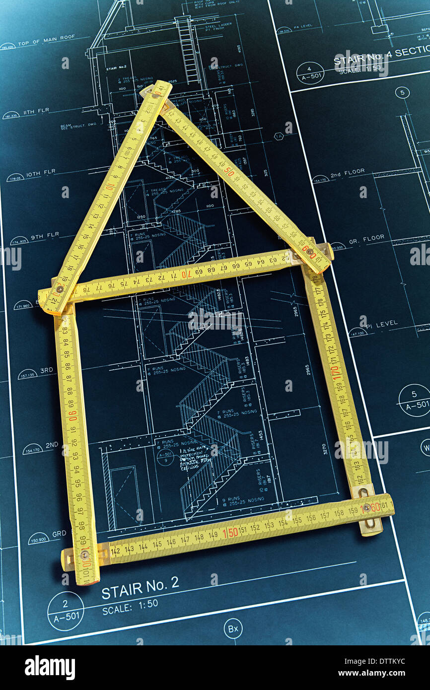 Rulers forming house over construction blueprints Stock Photo - Alamy