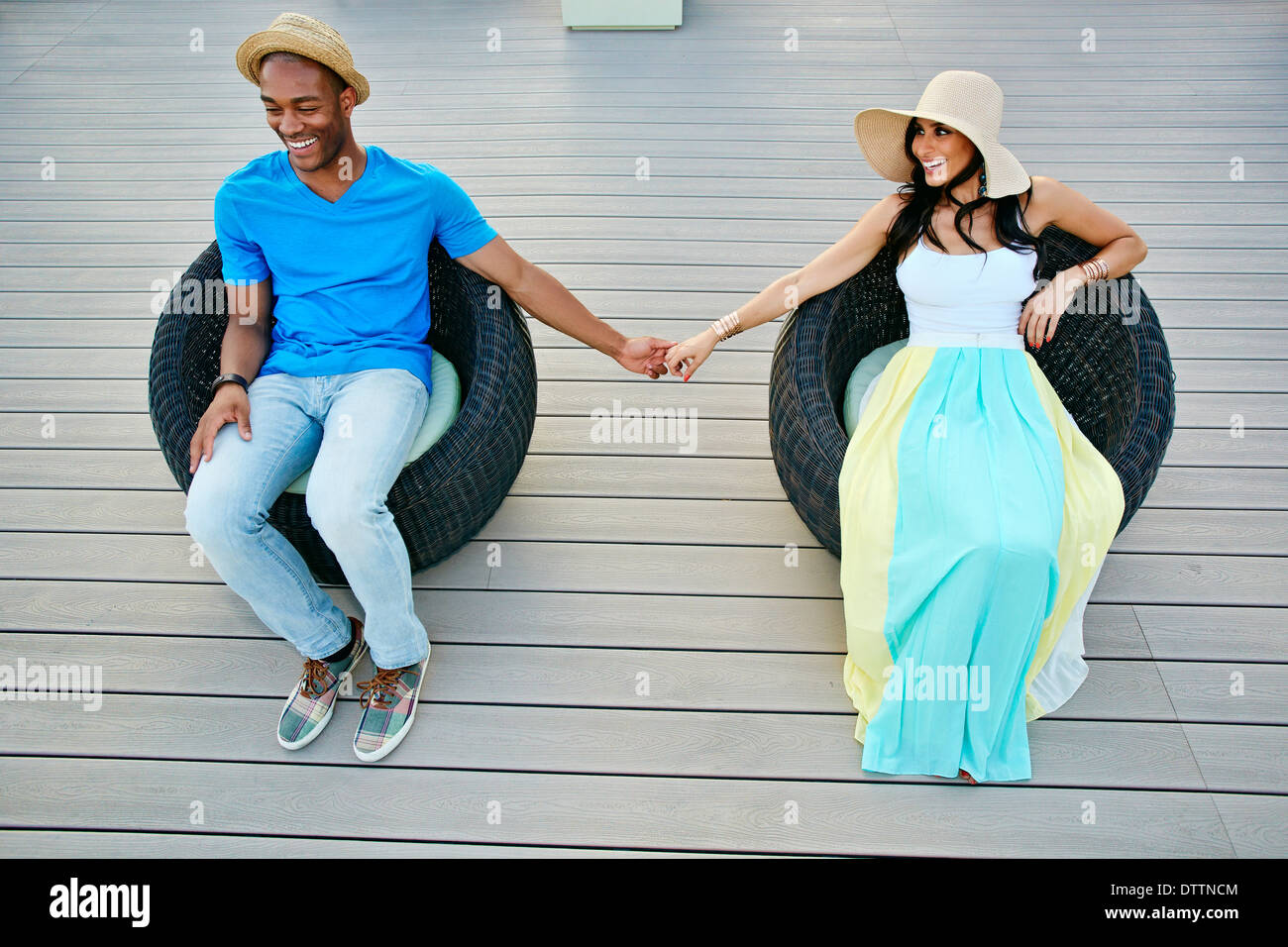 Couple holding hands in wicker chairs Stock Photo - Alamy
