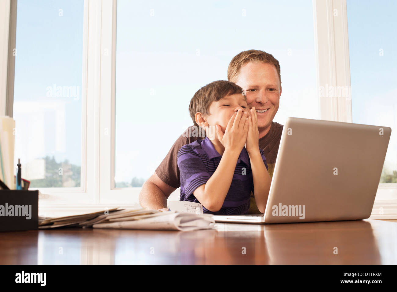 Father and son using laptop at desk Stock Photo - Alamy
