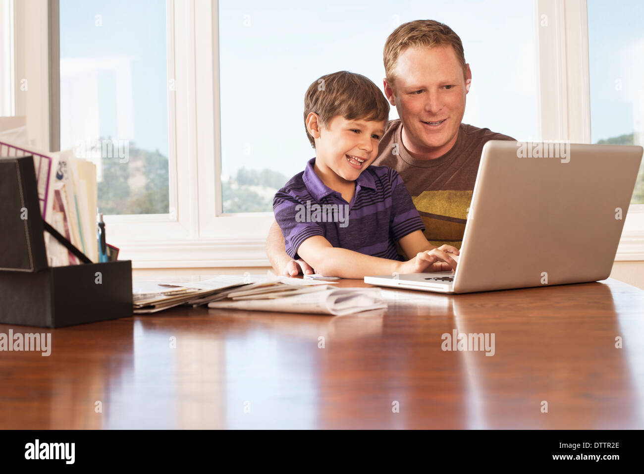 Father and son using laptop at desk Stock Photo - Alamy